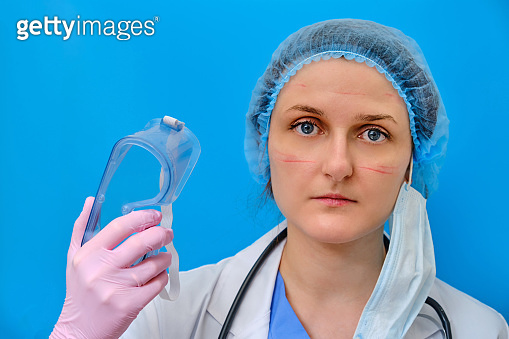 A doctor with a wounded face removes goggles after working in the ...