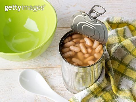 Canned backed beans in an open tin can with pull tab near ceramic bowl ...