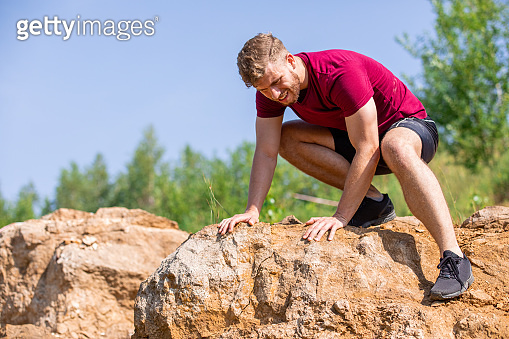 Runner climbing on rocks obstacles in the extreme cross-country race ...