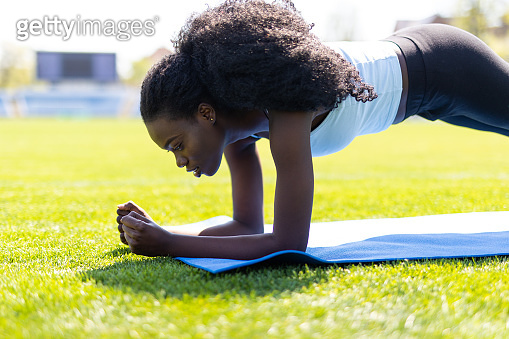 Beautiful African-American woman in sports clothing demonstrating plank ...
