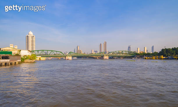 Memorial Bridge, and Phra Pok Klao Bridge with buildings and Chao Phraya River at noon. Urban ...