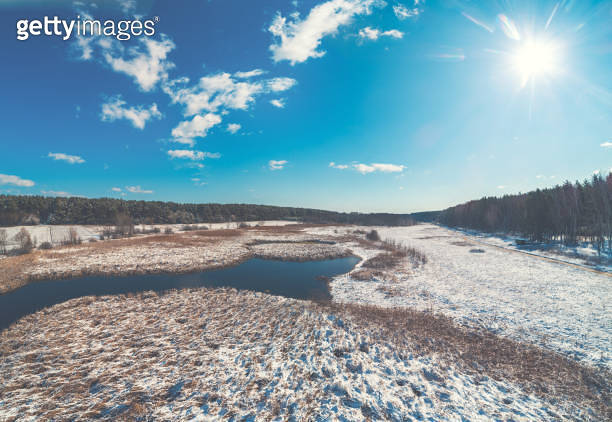 View from above of the countryside and brook on a sunny day. Snowy ...