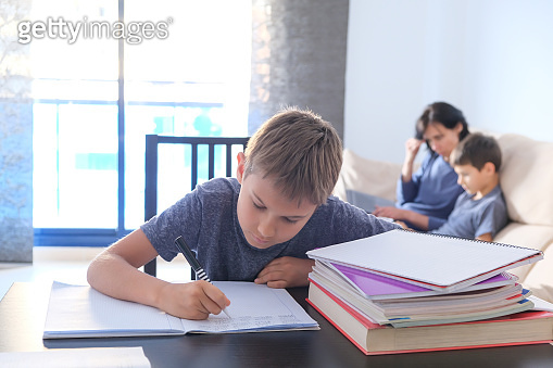 Children doing homework at home. Mother helping her son with homework ...
