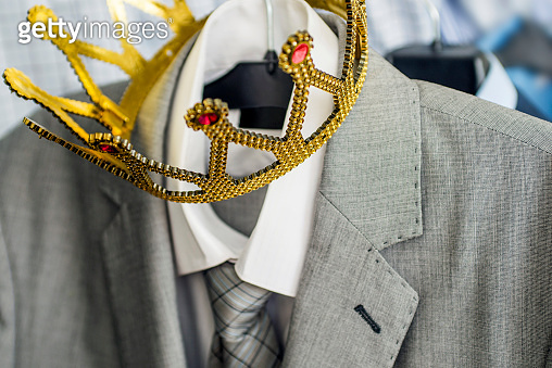 Business suit with a gold crown hanging on a hanger. Clothing is a ...
