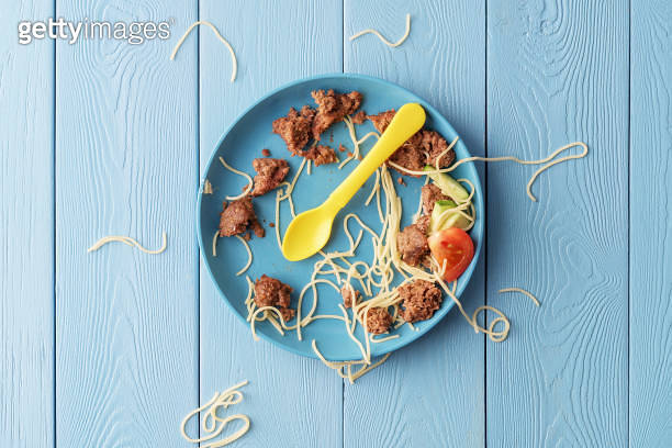 The concept of child feeding. Plate with under-eaten and scattered food ...