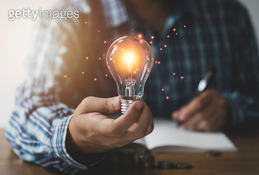 Businessman hand holding lightbulb with orange glowing and connection line. Creative thinking ...