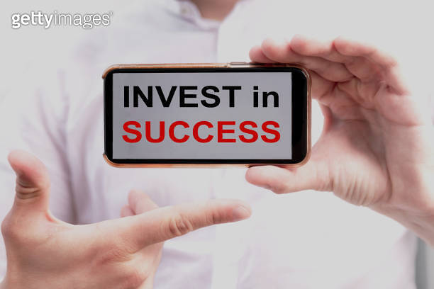 Businessman holding a phone with a message text invest in success ...