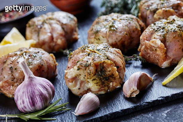 raw rabbit ballotine prepared to be cooked on a black slate plate ...