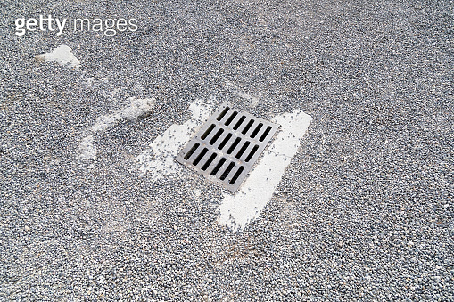 street gully grid on a gravel path with protruding stones 이미지 ...