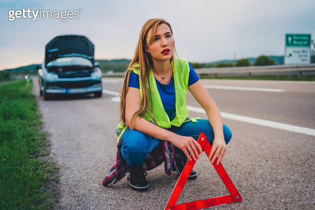 Woman putting triangle warning sign on road 이미지 (1227242778) - 게티이미지뱅크