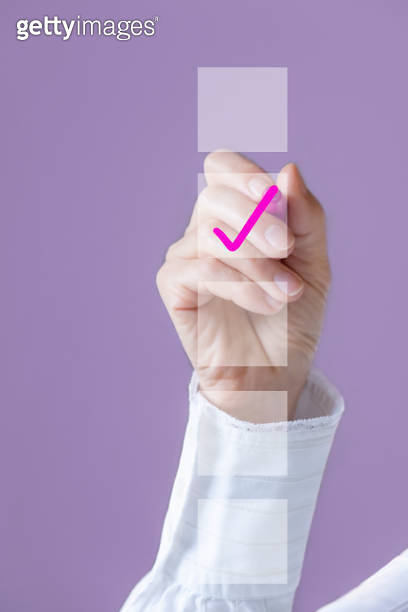Checklist. Businesswoman hand drawing a pink check mark in one checkbox ...