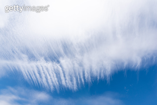 Long white wisps of clouds flowing with a large rippled cloud ...