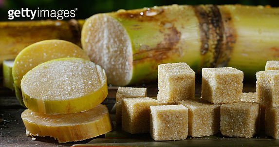 A macro shot of a composition of sugar cane, sugar cubes and sugar in ...