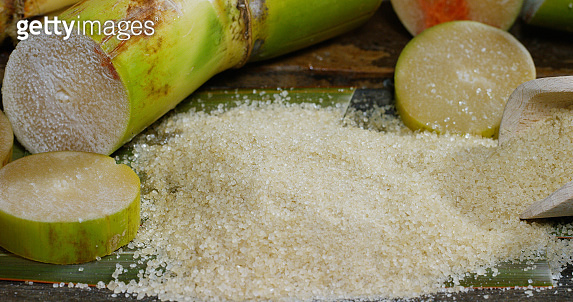 A macro shot of a composition of sugar cane, sugar cubes and sugar in ...