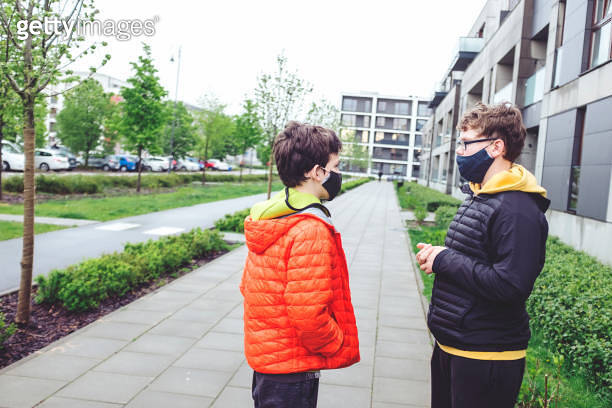 two cute teen brothers talking to each other in a street wearing ...