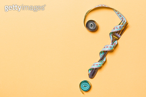 Top view of question mark made of fork and measuring tape on pink ...