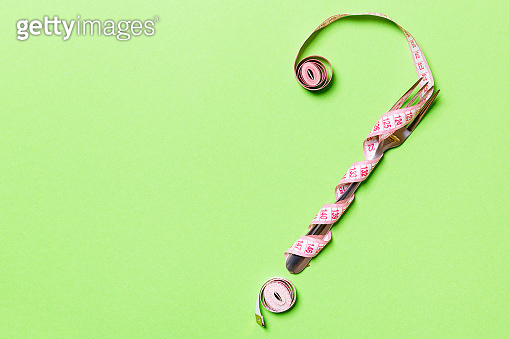 Top view of question mark made of fork and measuring tape on green ...
