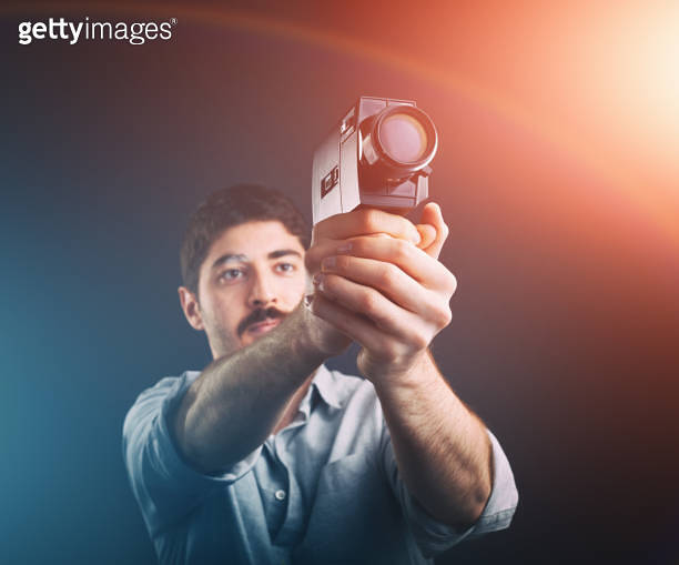 Young cinematographer shooting with an old fashioned film camera ...