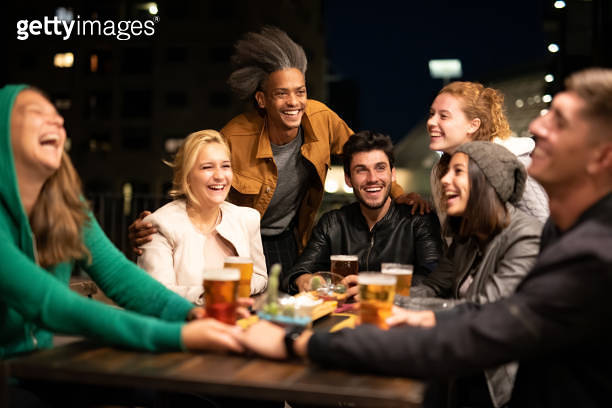 group of friends of different ethnicities meeting to toast with pints ...