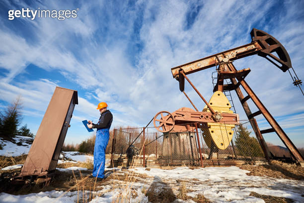 Oil well operator working in oil field with pump jack. (1215993748 ...