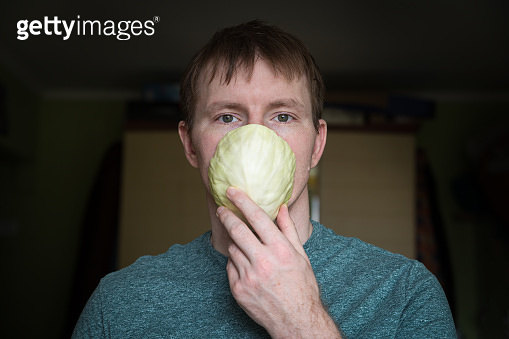 The young man covers his nose and mouth with a cabbage leaf instead of ...