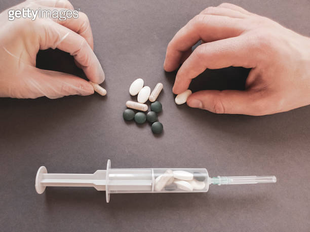 Medicine. Two hands take one pill on both sides from the pile. The ...