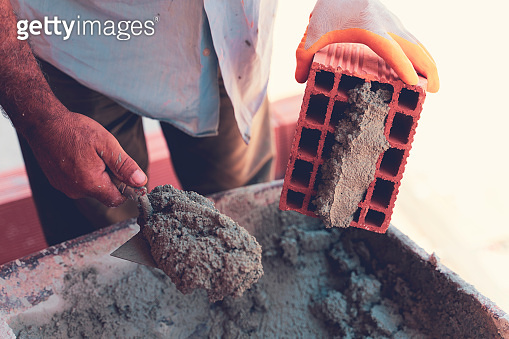 Bricklayer builder working. Walling, installing bricks on construction ...