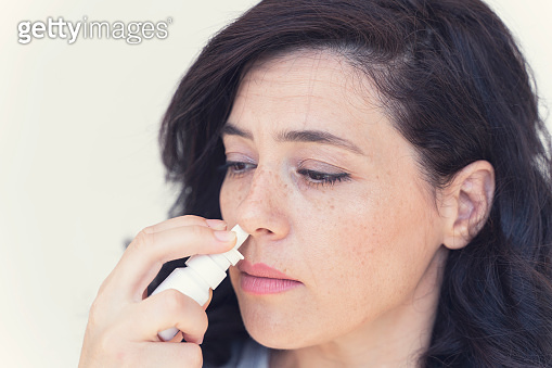 Female doing nasal irrigation by using normal saline solution spray ...