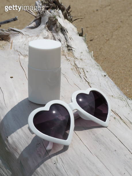 Beach essentials: heart shaped sunglasses and a bottle of sunscreen on ...