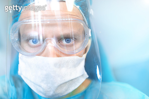 Medical surgeon in uniform and face shield in the operating room during ...