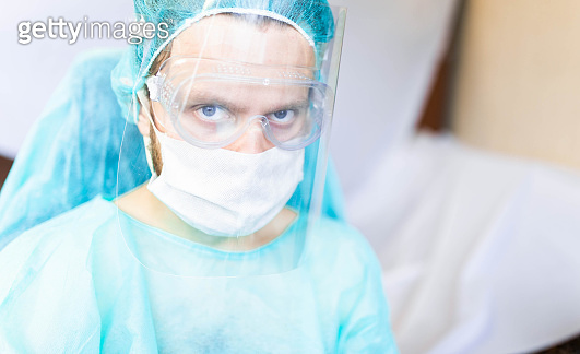 Medical surgeon in uniform and face shield in the operating room during ...