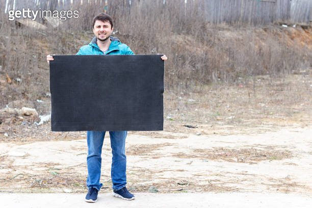 Handsome smiling man with a rectangular black piece of dense fabric in ...