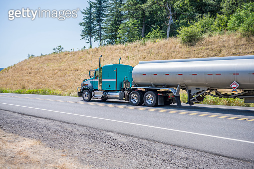 Powerful big rig semi truck tractor transporting fuel in long tank semi ...