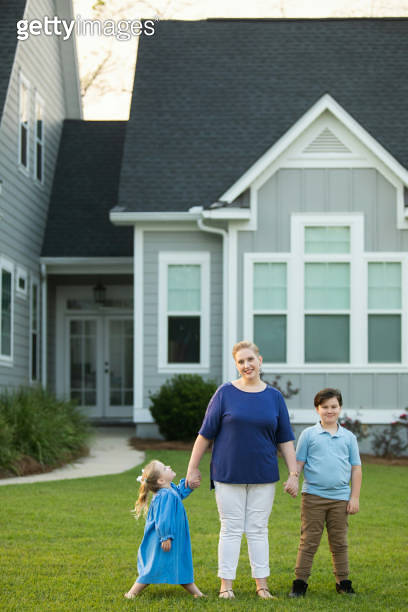 A Single mom outside the front of a new construction gray house with ...
