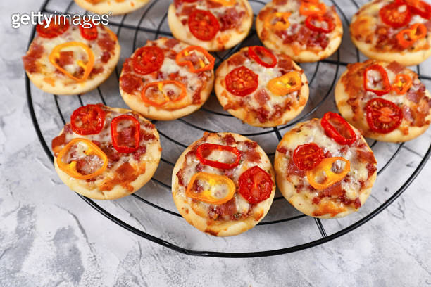 Small mini pizzas topped with cheese, tomato, yellow and red bell ...