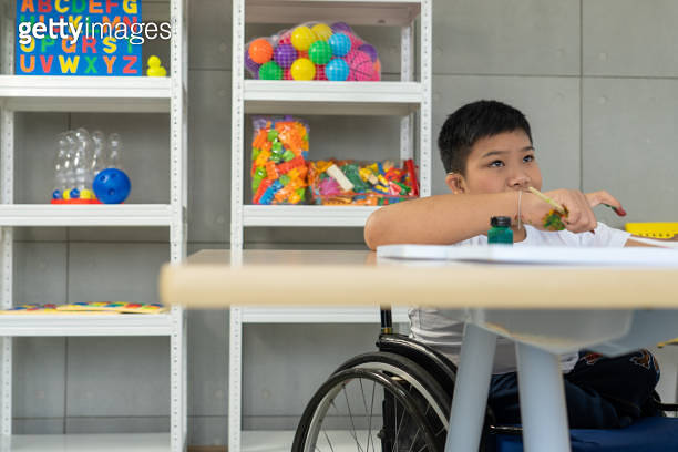 Disabled child on wheelchair learning at his desk in class room. 이미지 ...