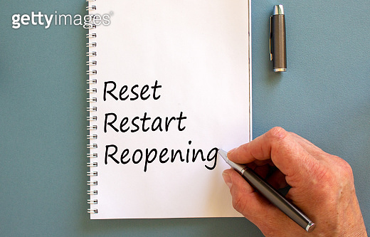 Male hand writing 'reset, restart, reopening' on white note, isolated ...