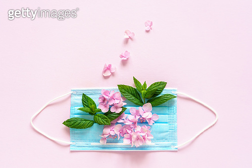 Blue face mask with small flowers and fresh peppermint on a pink ...