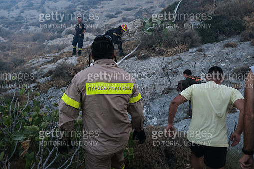 Firefighters and volunteers work to extinguish a fire in Santorini ...