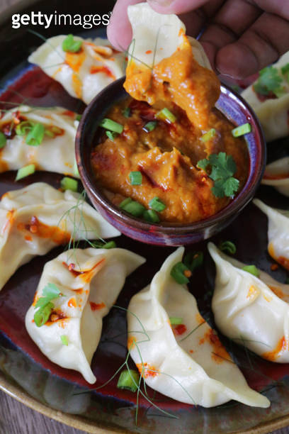 Close-up image of unrecognisable person holding half eaten steamed Momo ...