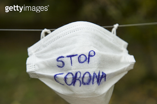 One protective white face mask hanging in rope. Stop corona writes on ...