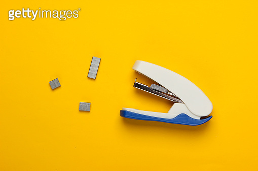 Stapler with paper clips on yellow background. Minimalism. Top view ...