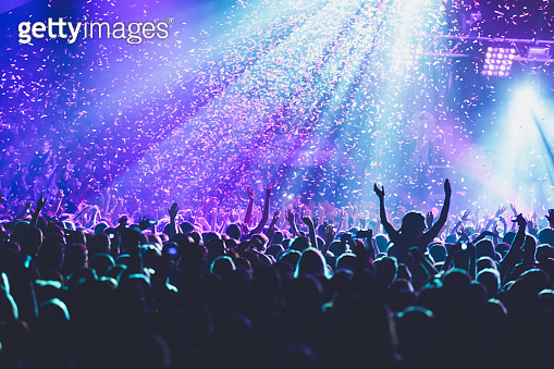 A crowded concert hall with scene stage lights, rock show performance ...