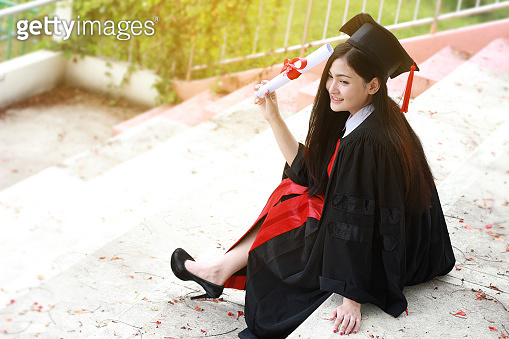 Happy graduated student wearing a black hat, holding certificate on ...