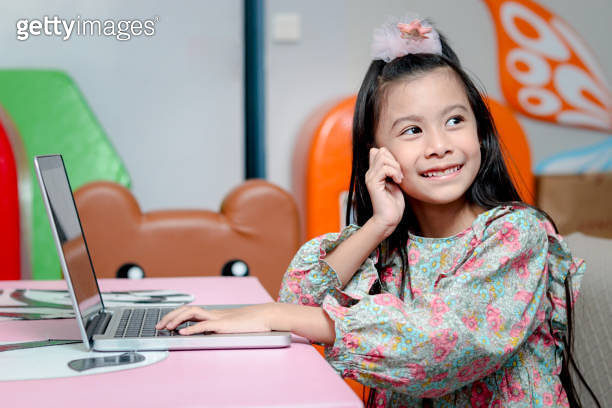 Kid (a girl) with laptop computer, distance learning online education at home, new generation of ...