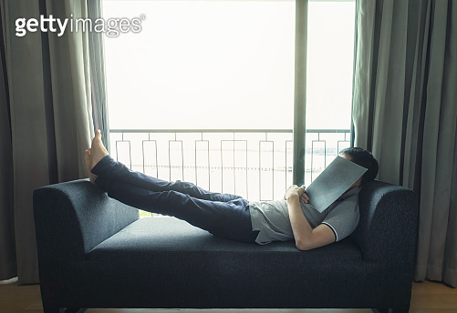 Man resting on modern sofa beside window 이미지 (1220609711) - 게티이미지뱅크
