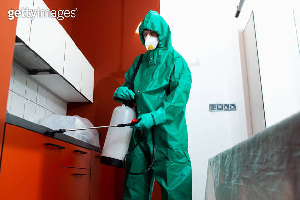 Man sanitizing frequently touched surfaces in the kitchen stock photo ...