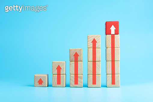 Wooden blocks stacking as step stair with red arrow up, blue background ...