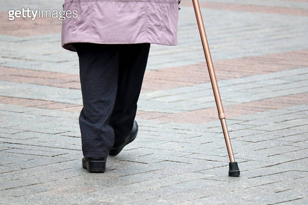 Limping woman walking with a cane down the street 이미지 (1270418744) - 게티 ...