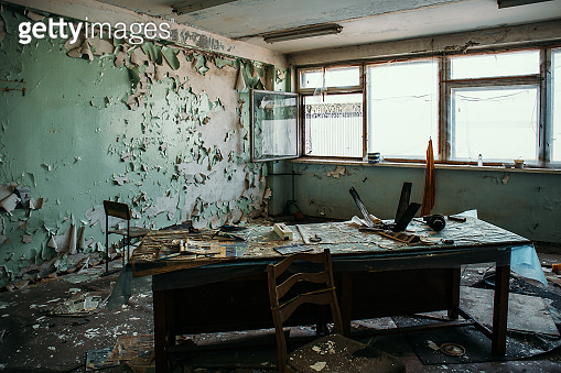 Creepy abandoned office room inside with old wooden table and windows ...